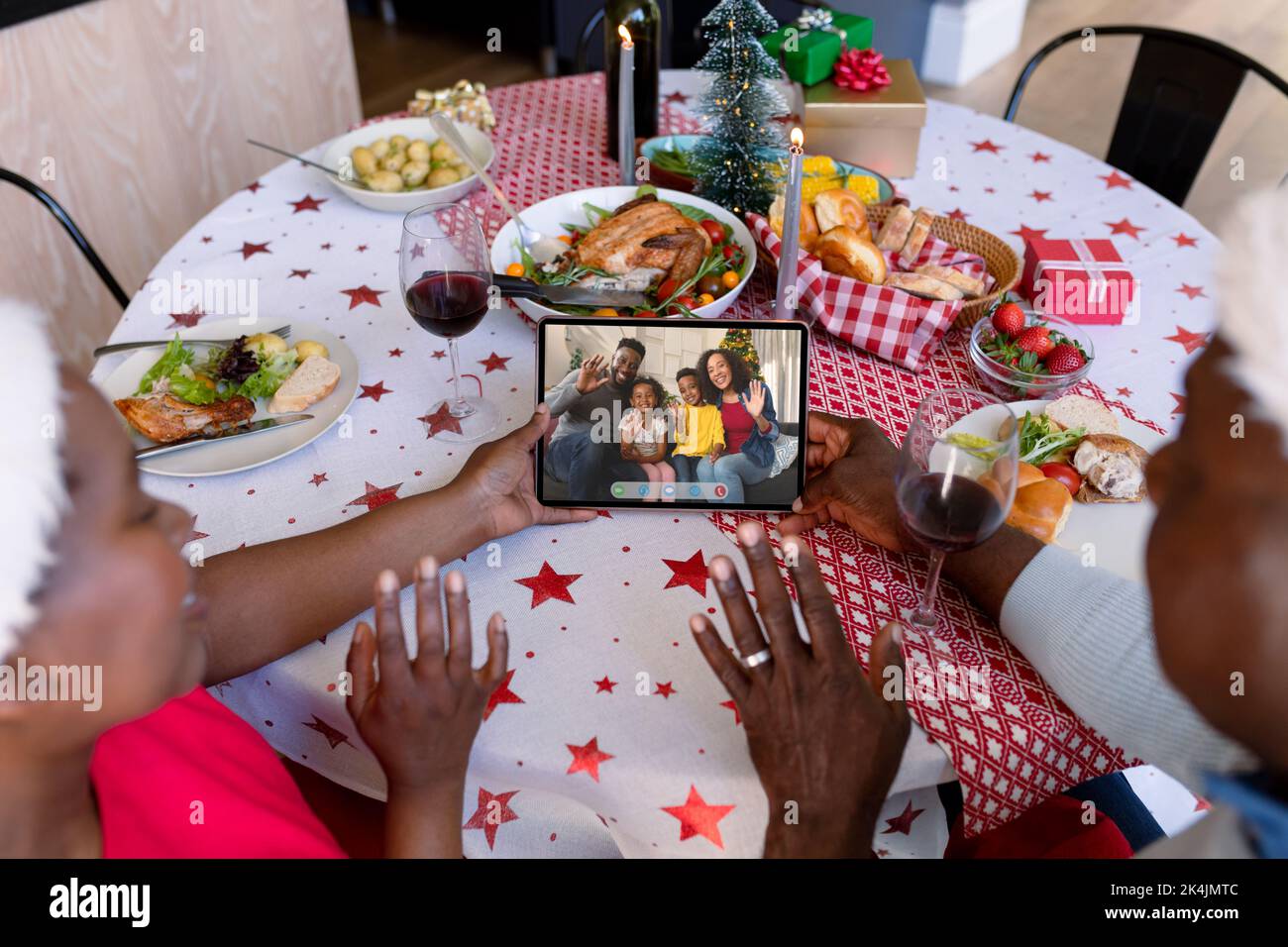 Waving african american couple in santa hats making christmas tablet ...