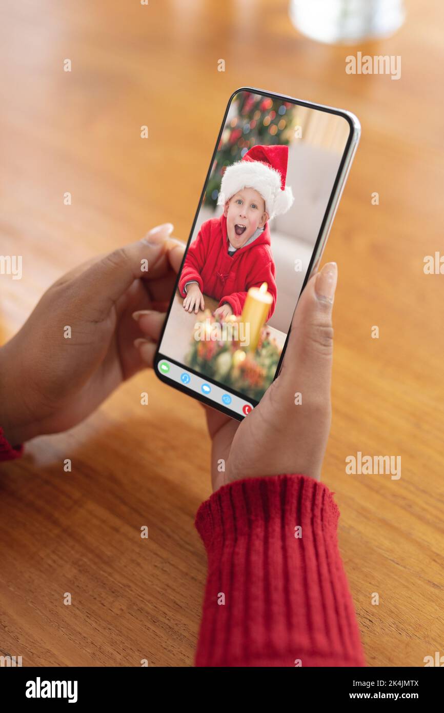 Hands holding smartphone with happy caucasian boy in christmas santa ...