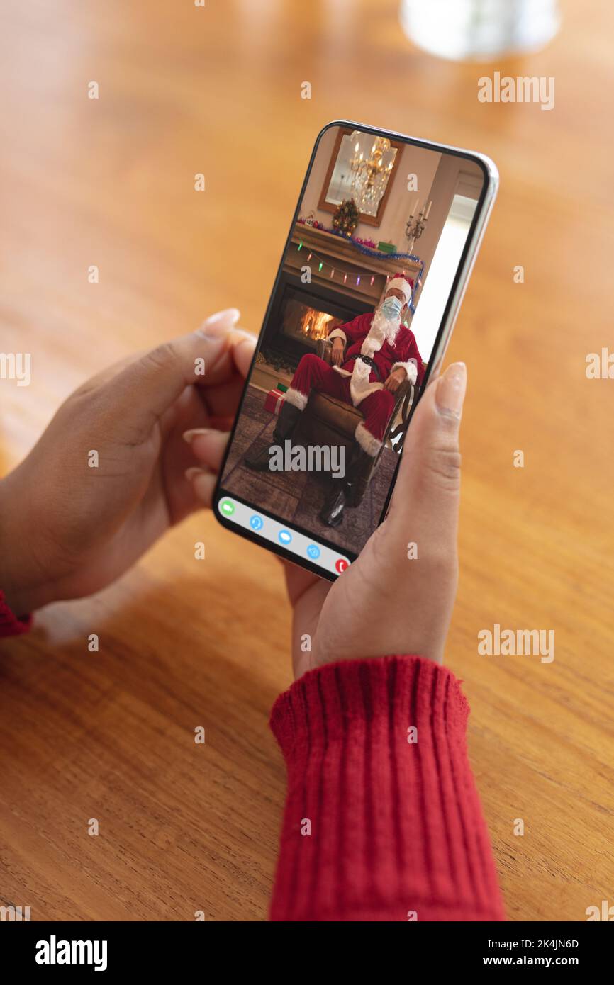 Hands of woman making christmas smartphone video call with santa claus ...