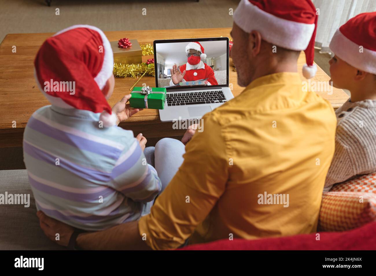 Caucasian father and sons making laptop christmas video call with santa ...