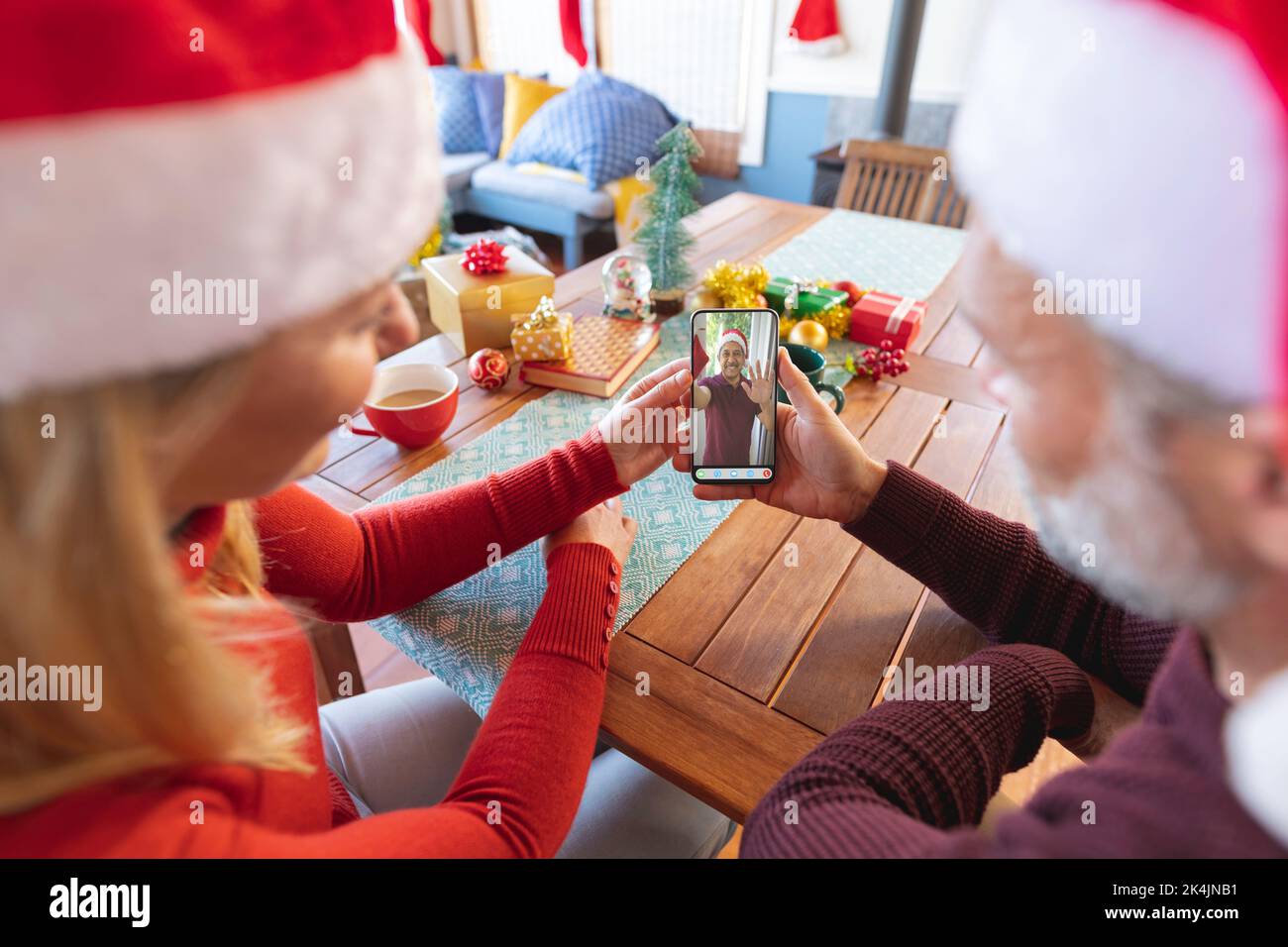Caucasian couple in santa hats making smartphone christmas video call ...