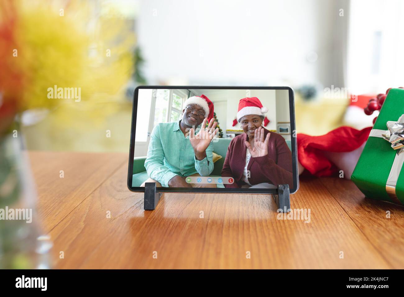 Happy senior african american couple in santa hats waving on tablet ...