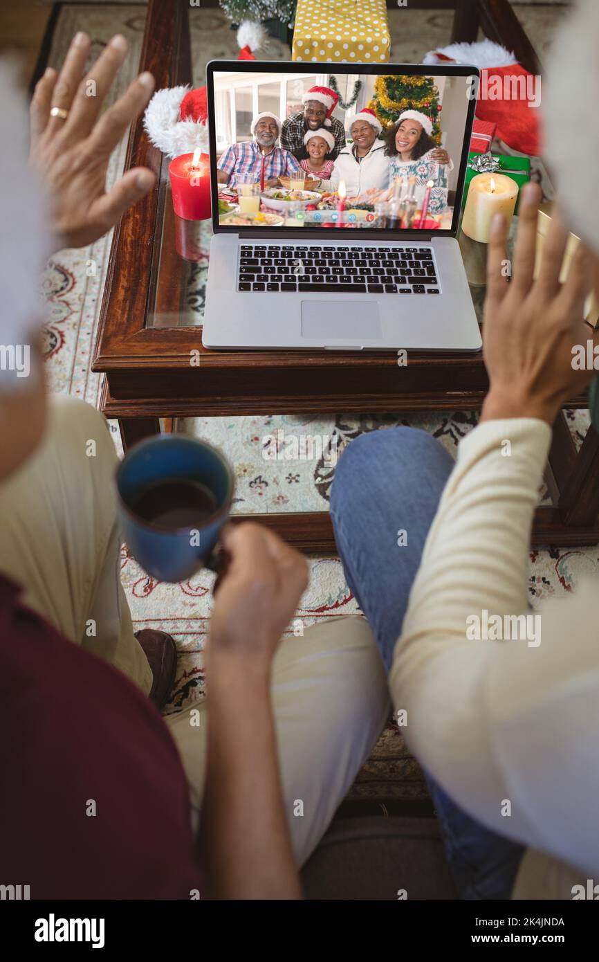 Two waving men making laptop christmas video call with smiling african ...