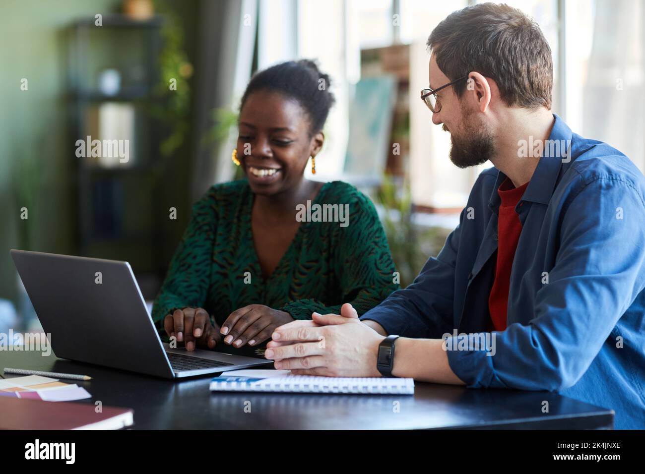 Young businessman looking at African American female colleague during ...