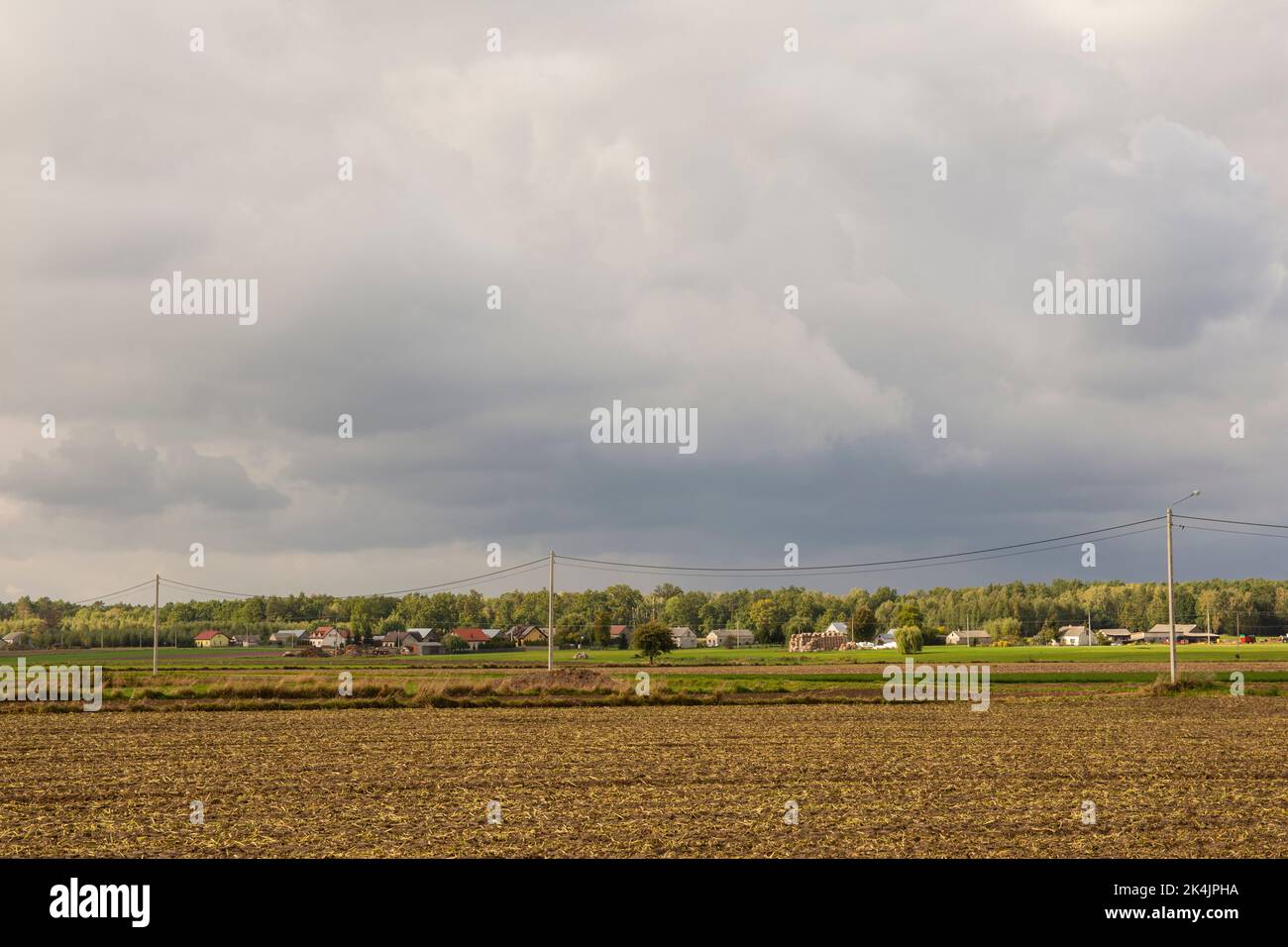 Dark clouds over the plowed field and the village in the background ...