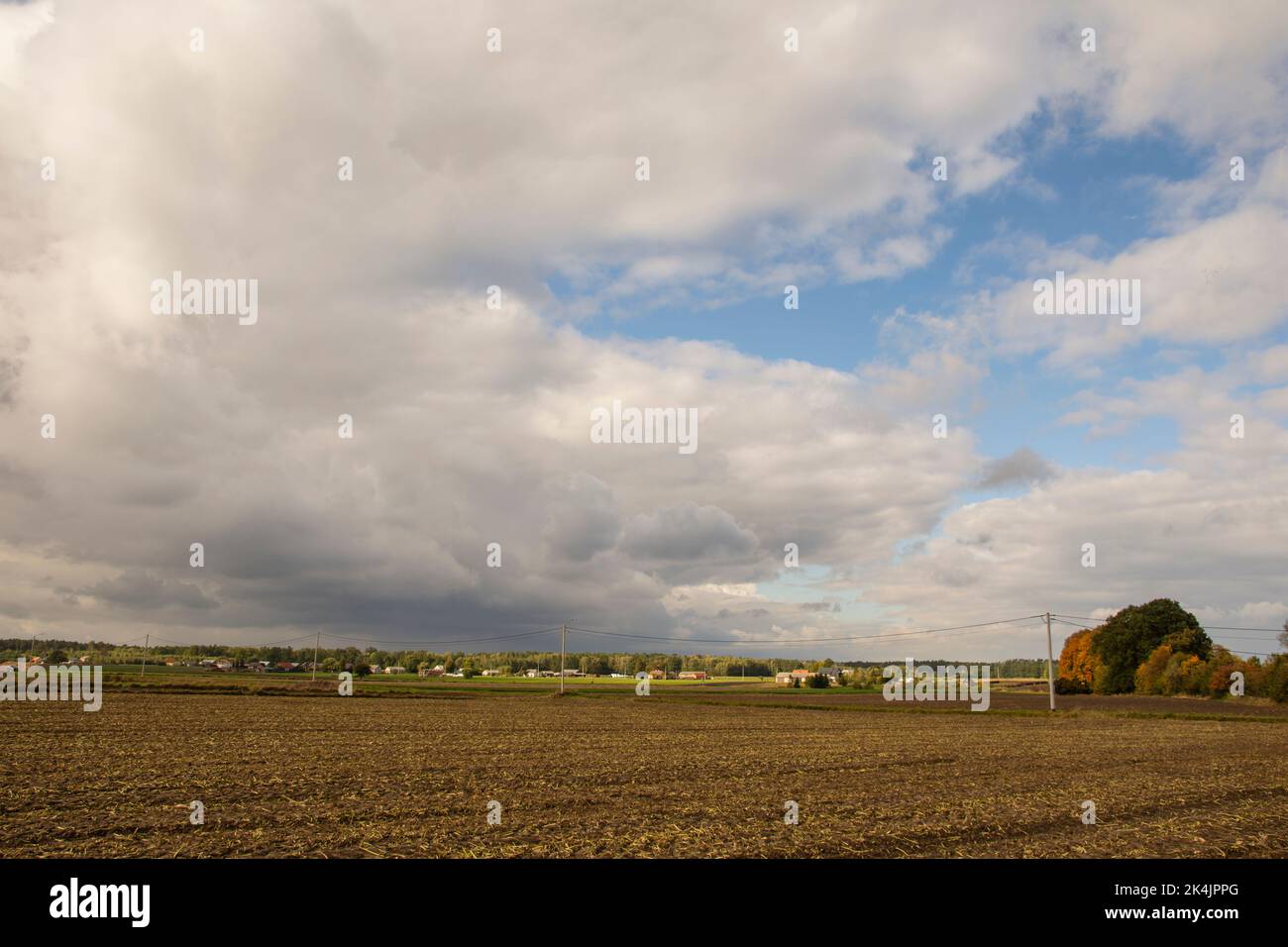 Dark clouds over the plowed field and the village in the background ...