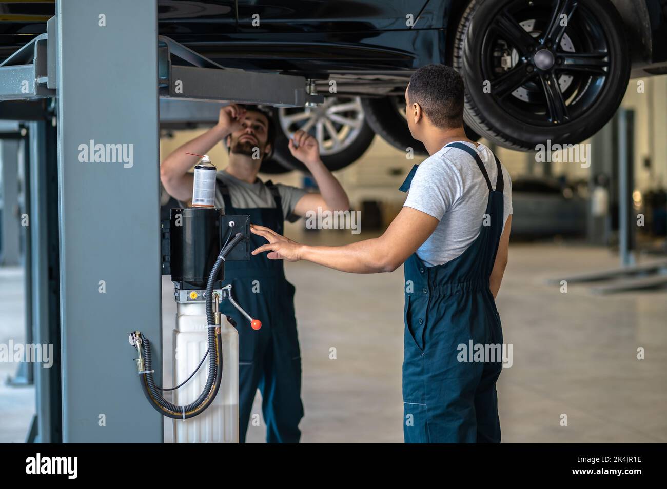 Two professional mechanics performing visual inspection of the vehicle ...