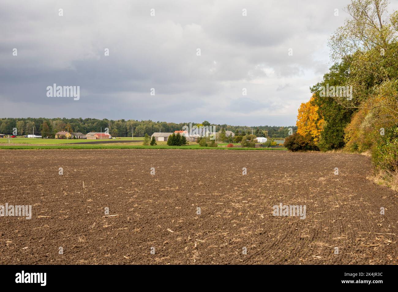 Dark clouds over the plowed field and the village in the background ...