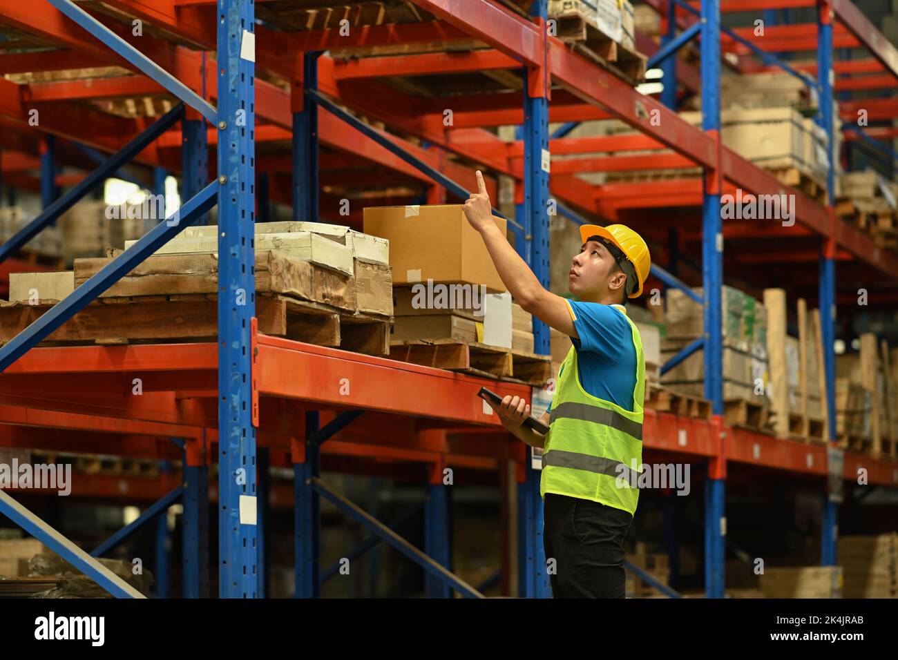 Young asian male warehouse worker checking stock, counting boxes on ...