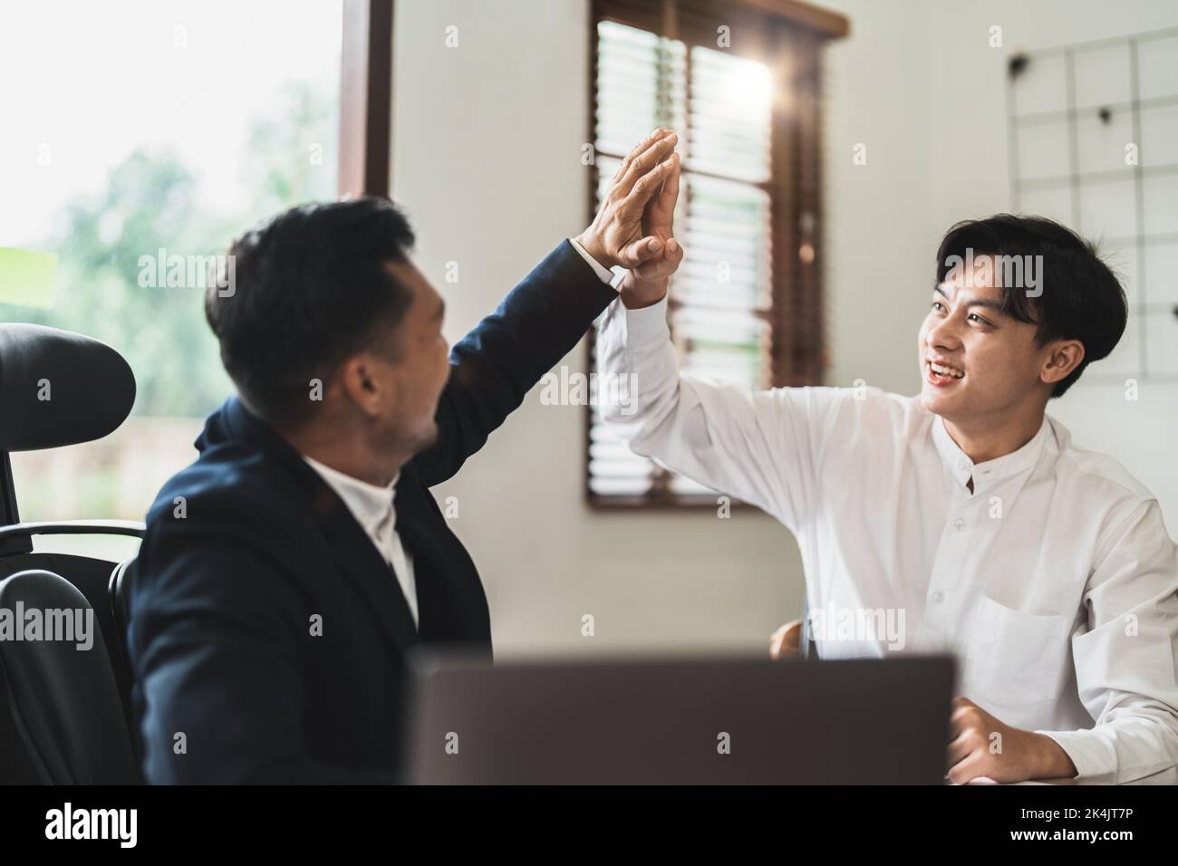 Smiling male colleagues celebrate shared success. Working together with ...