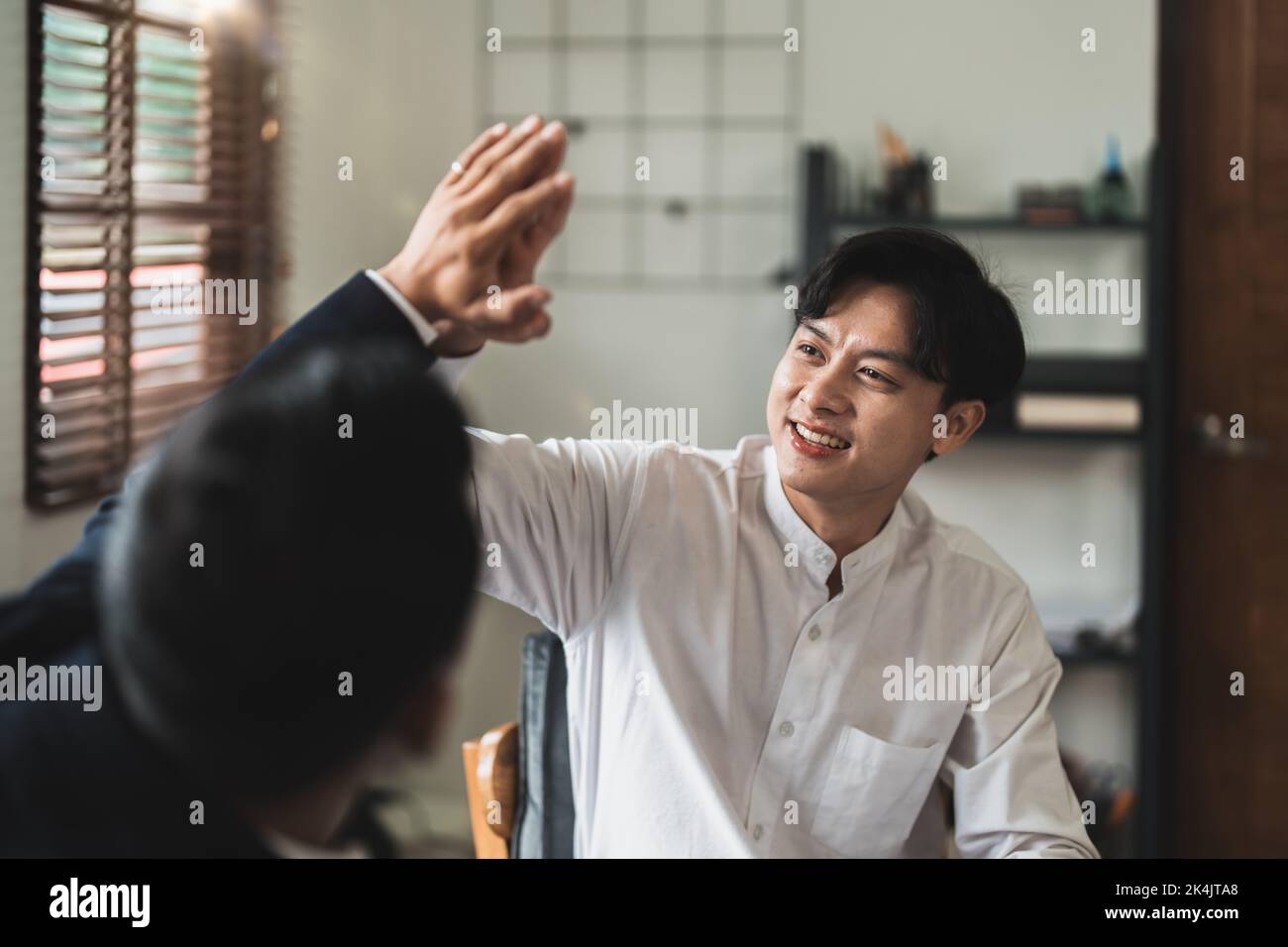 Smiling male colleagues celebrate shared success. Working together with ...