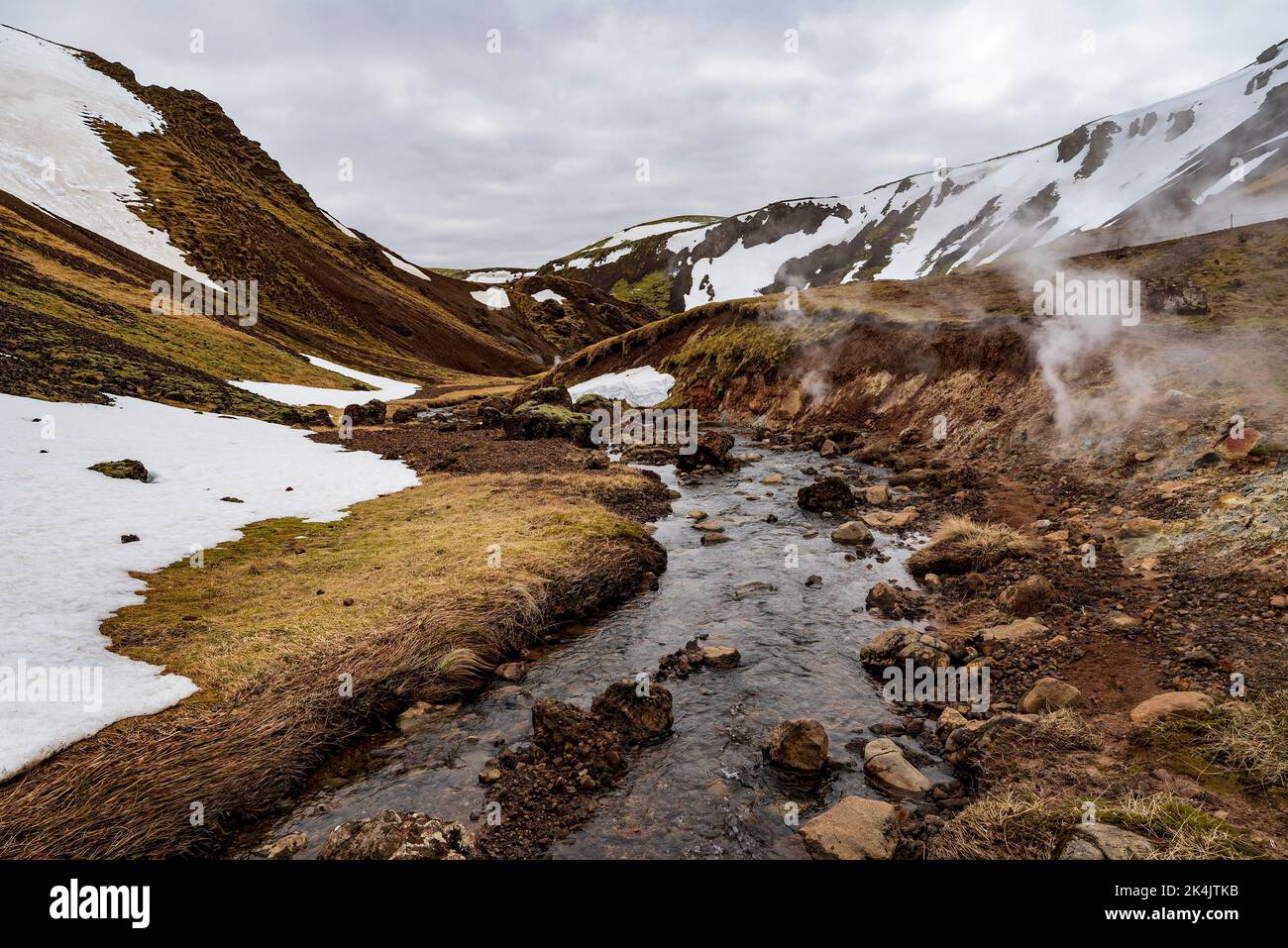 Steam rises over the stream and the geothermal area in Klambragil gorge ...
