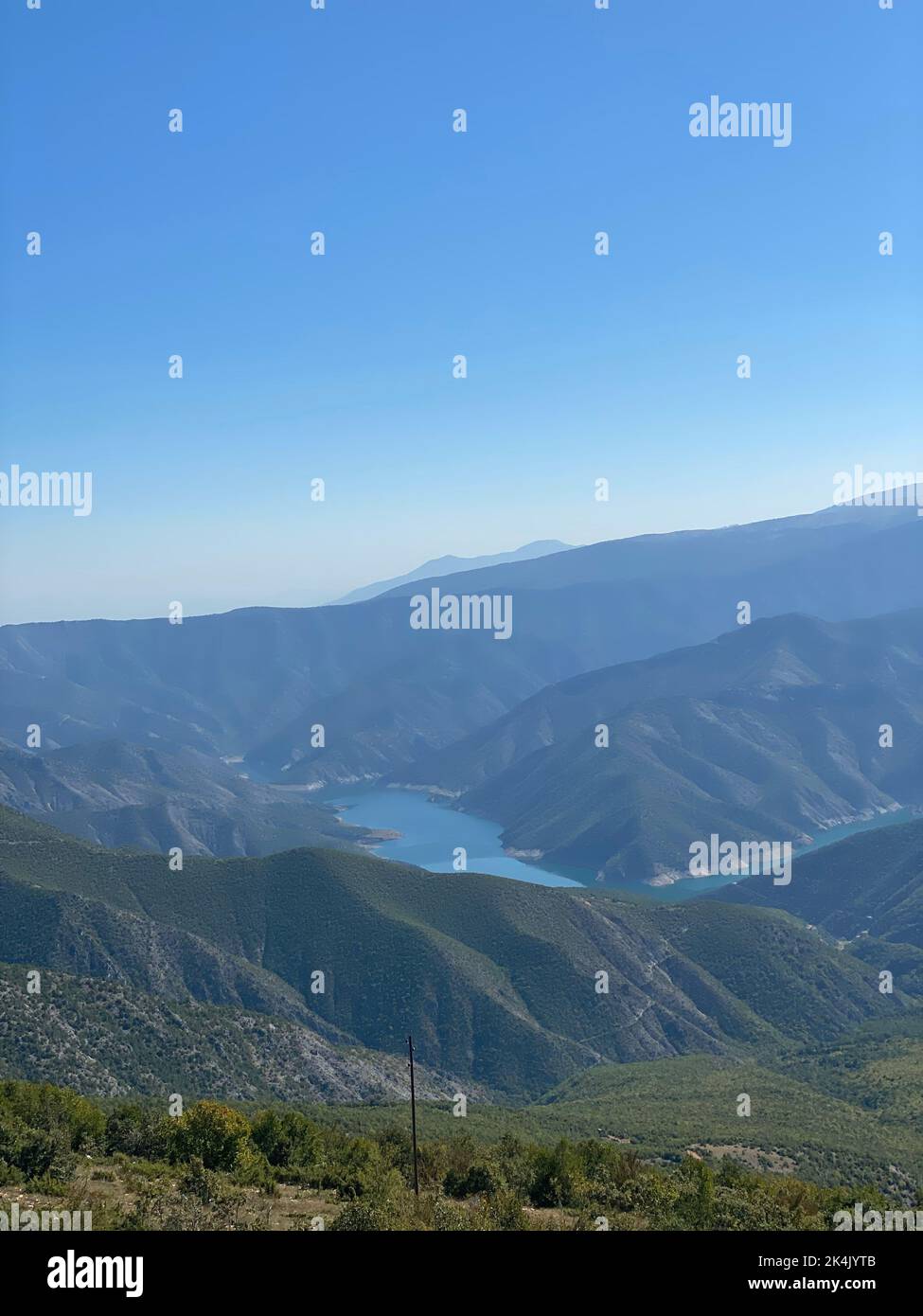 A vertical shot of green hills and river against the background of blue ...
