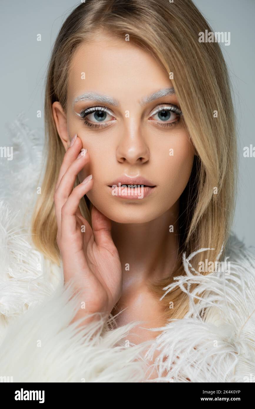 young model in winter faux fur jacket with feathers looking at camera ...