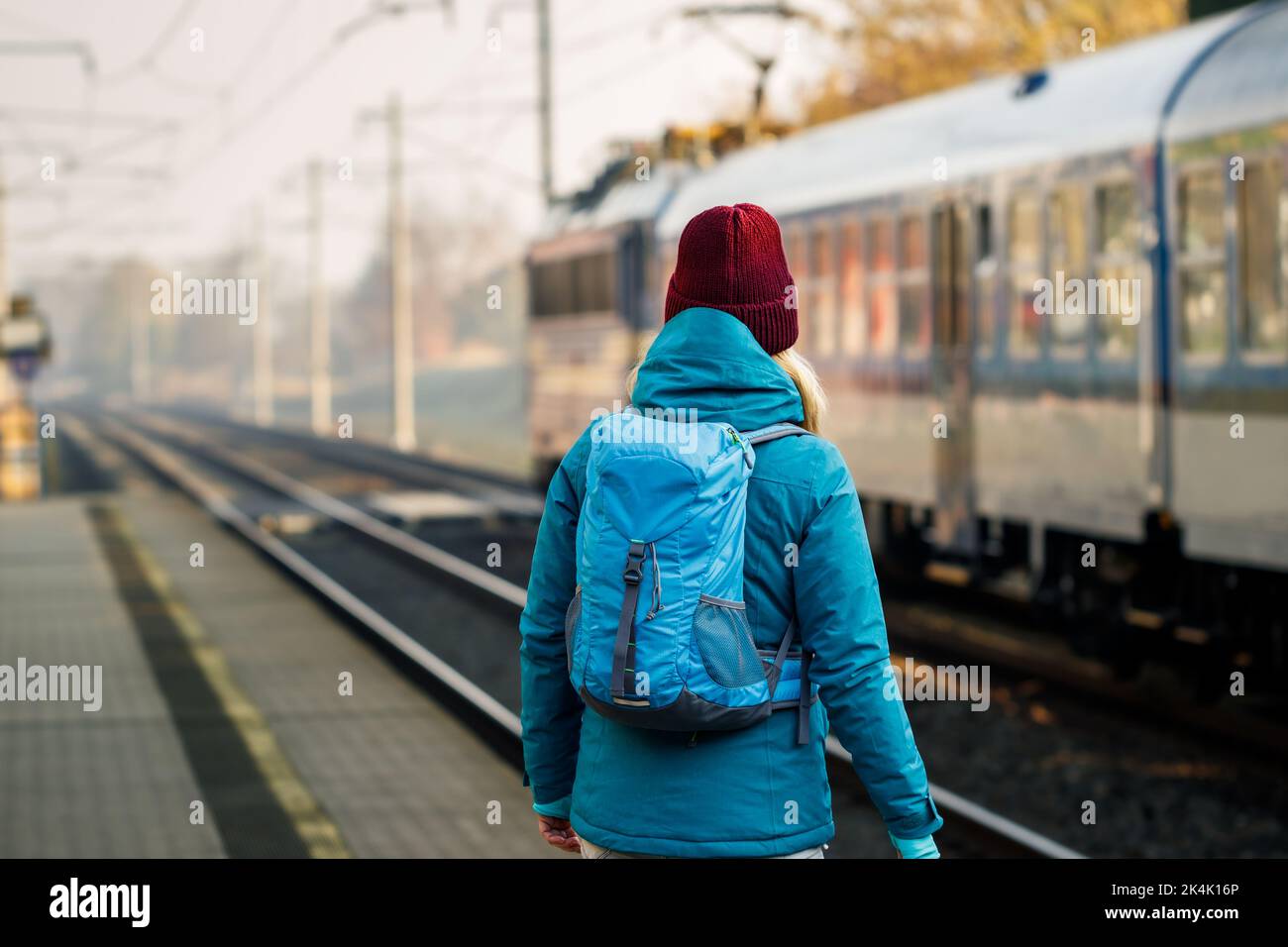 Woman looking at leaving train on railroad station. Female backpacker ...