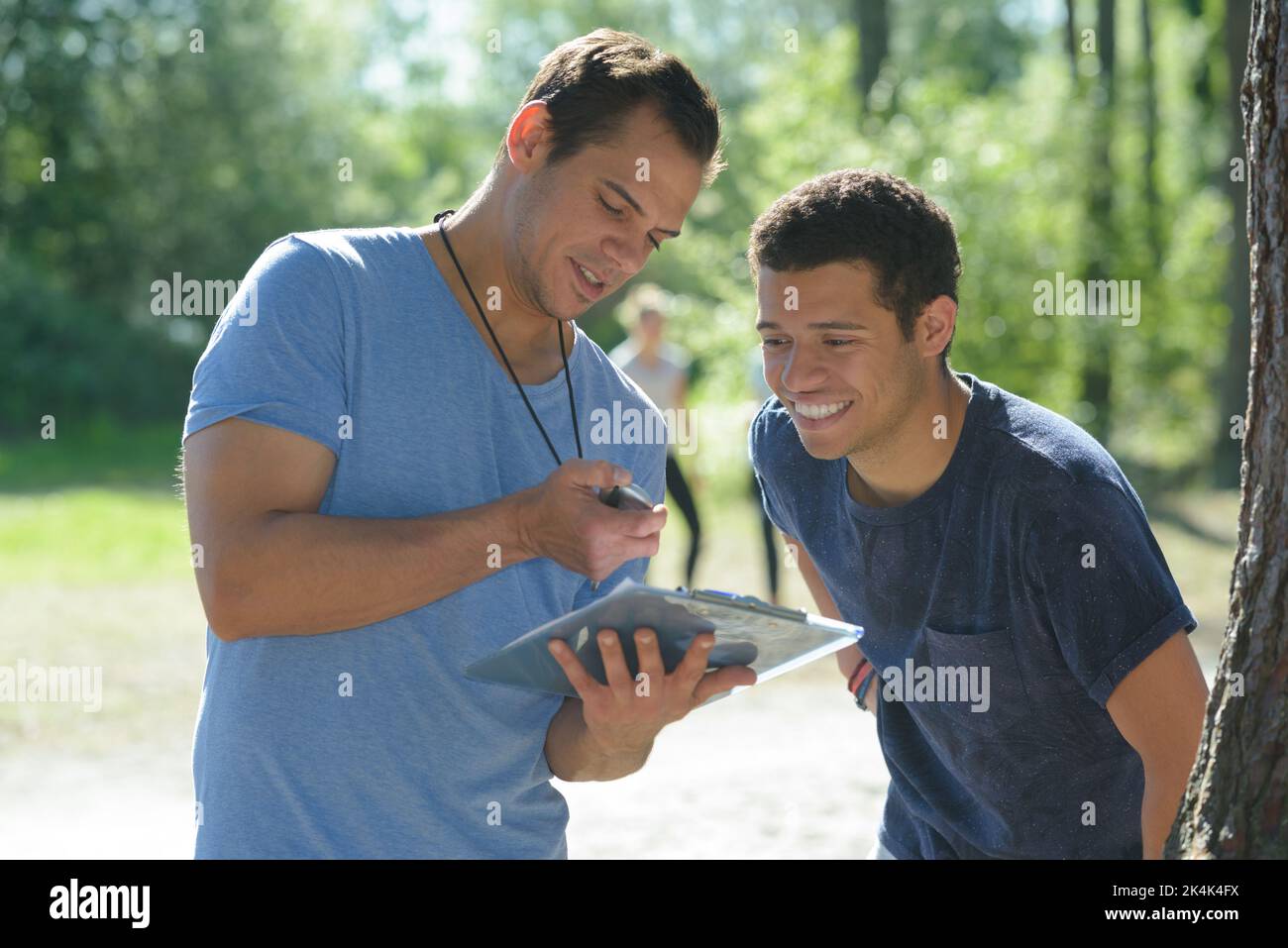 coach looking at stopwatch with young male runner Stock Photo - Alamy
