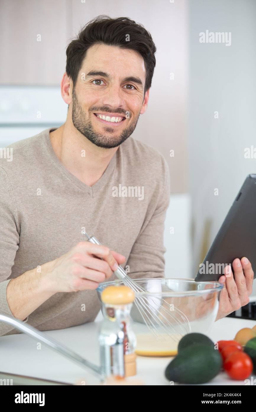 man preparing cake mixture while using tablet Stock Photo - Alamy
