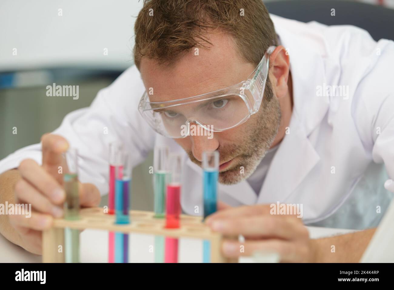 mask and goggles protected life science researcher observing liquid ...