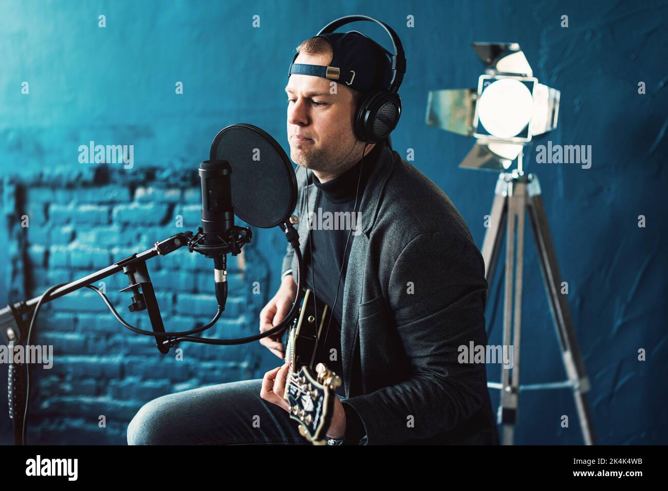 Close up of a man singer sitting on a stool in a headphones with a ...