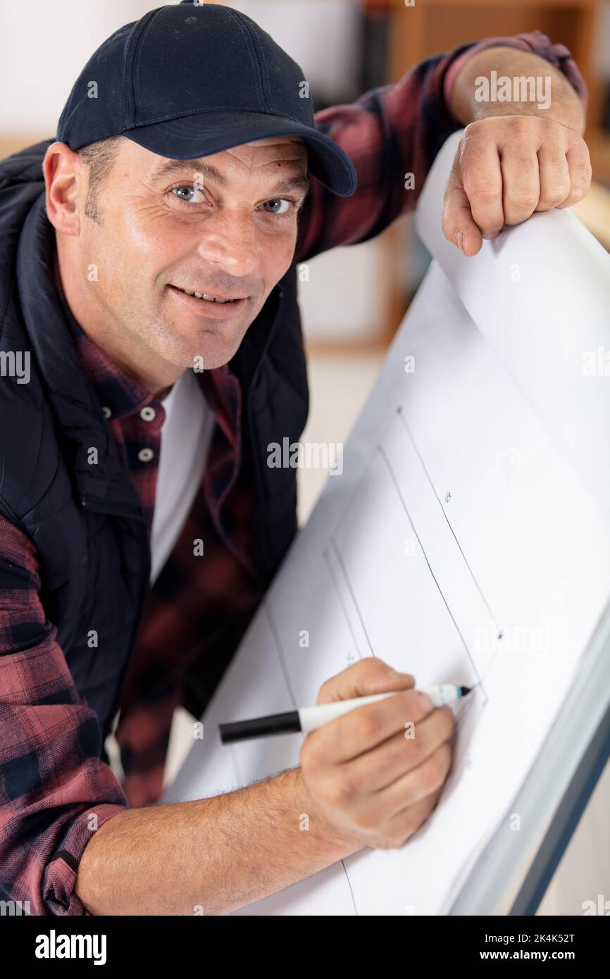 middle-aged workman drawing design on flip chart Stock Photo - Alamy