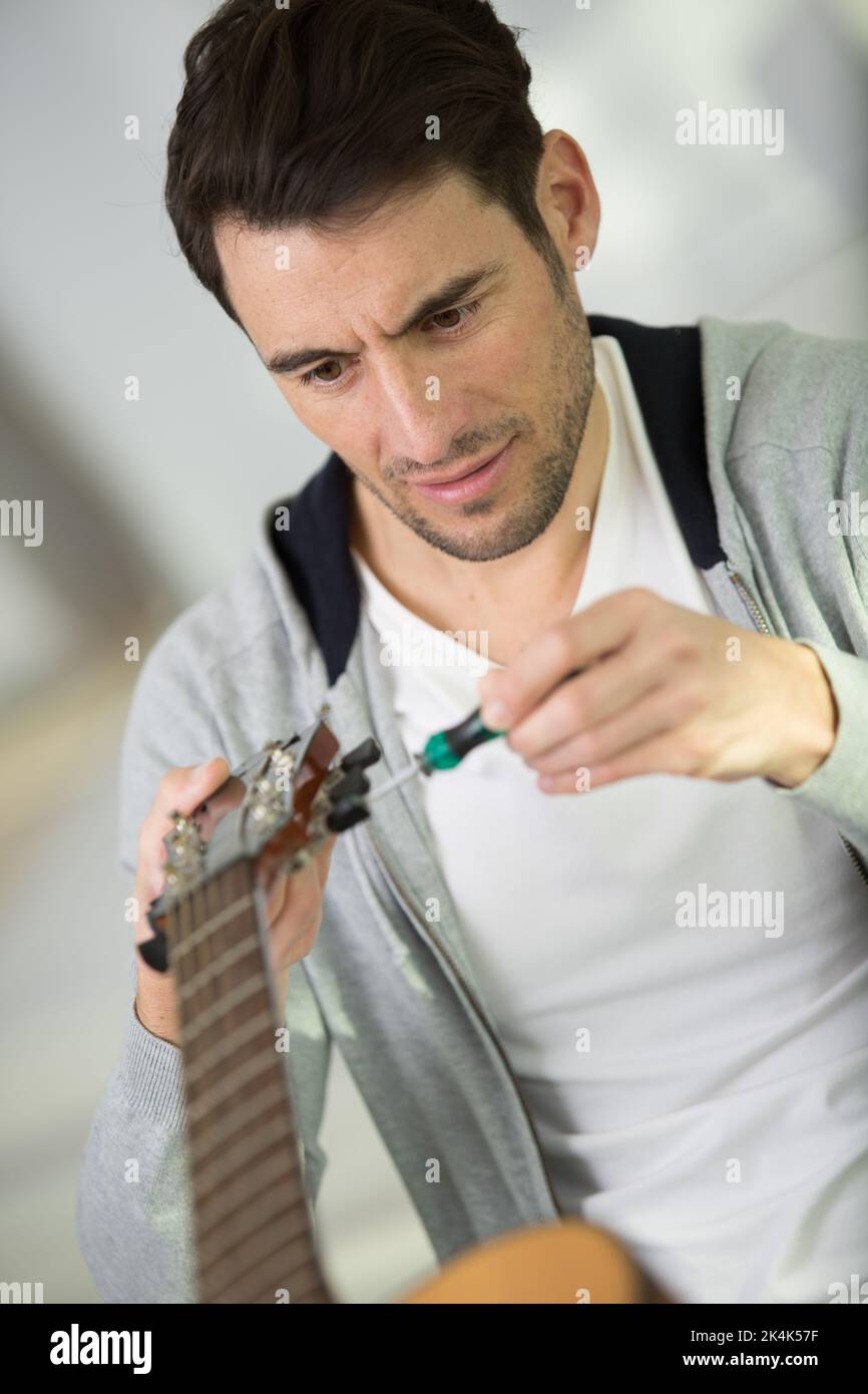 man using a screw driver on guitar Stock Photo - Alamy