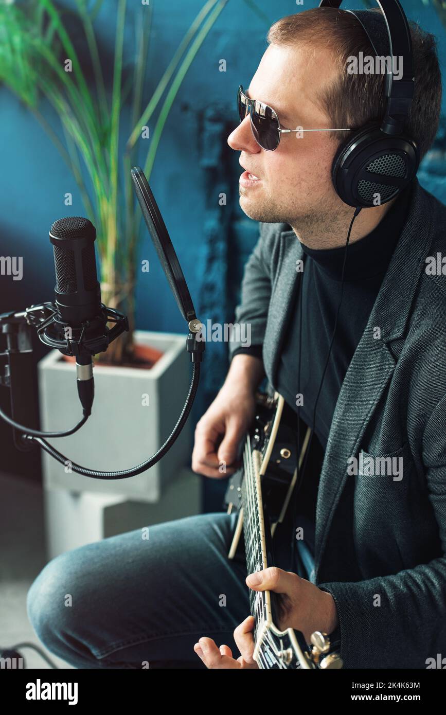 Close up of a man singer sitting on a stool in a headphones with a ...