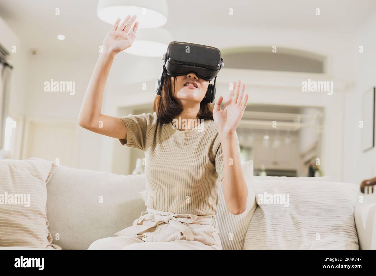 woman wearing VR and playing game on sofa at home Stock Photo - Alamy