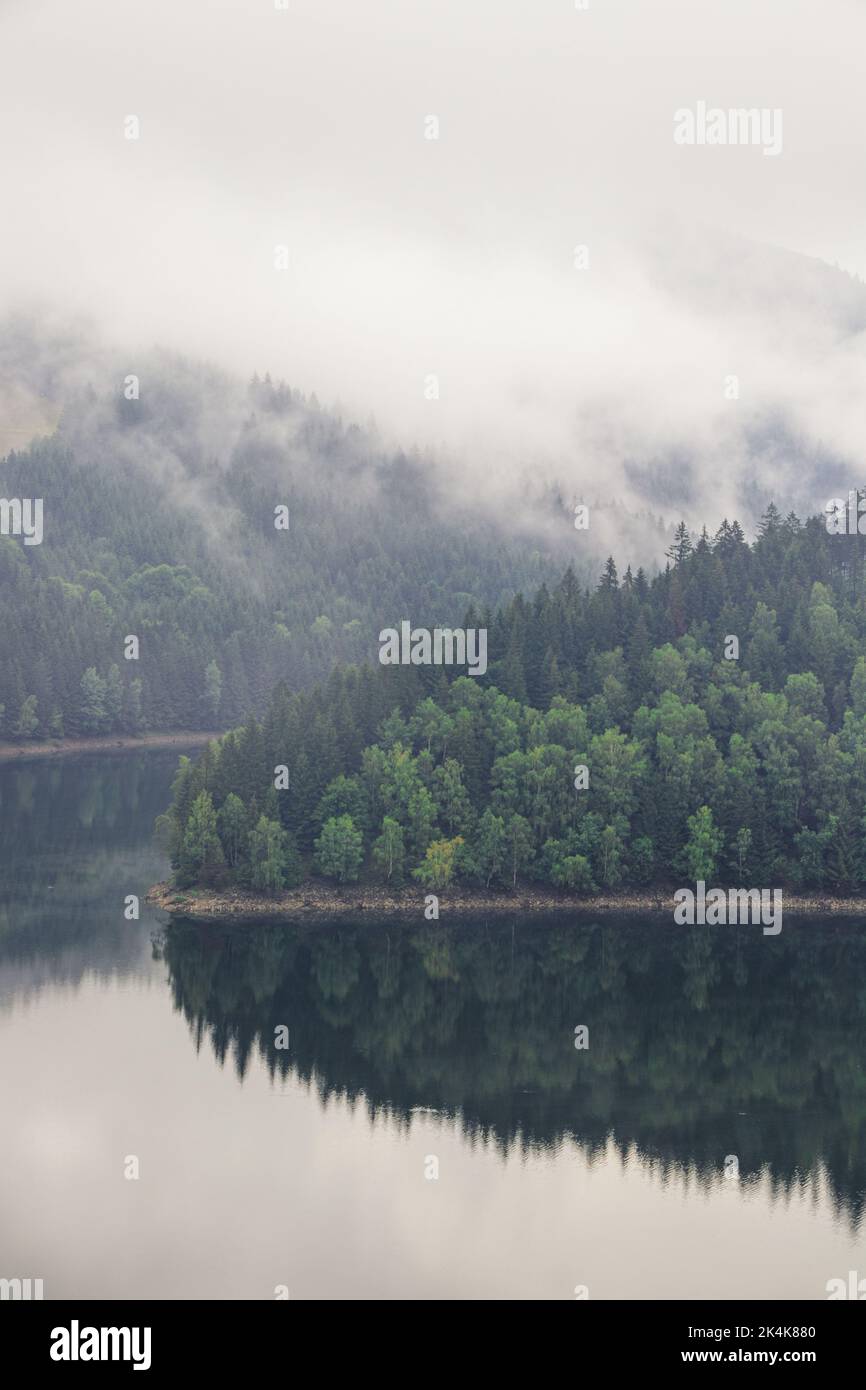 Rainy and foggy morning at the Sance Dam. Reflection of deciduous ...