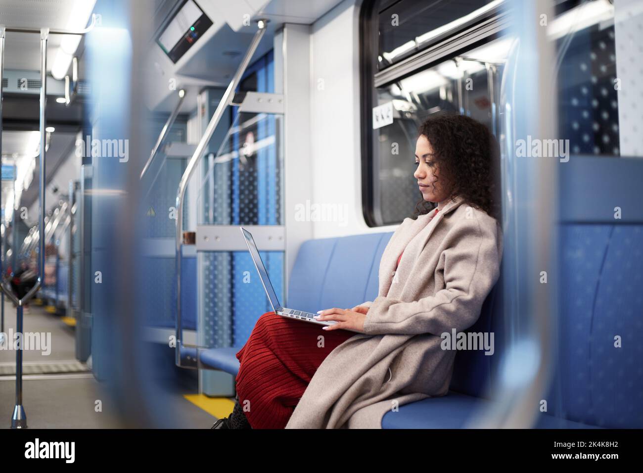 young woman using her laptop while riding the subway Stock Photo - Alamy