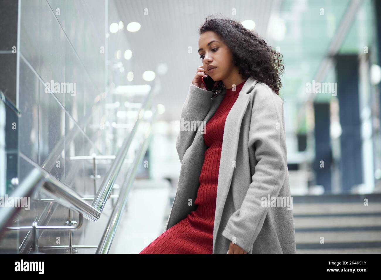 young woman talking on a mobile phone while standing in a subway tunnel ...