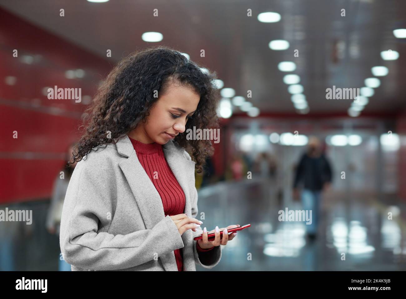 young woman reading a text message going up the escalator in the subway ...