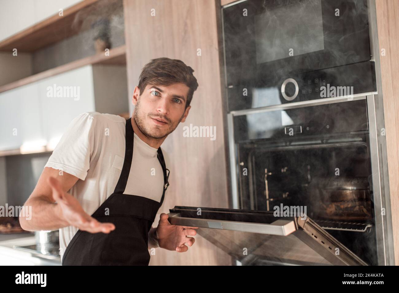 frustrated young man standing near broken oven Stock Photo - Alamy