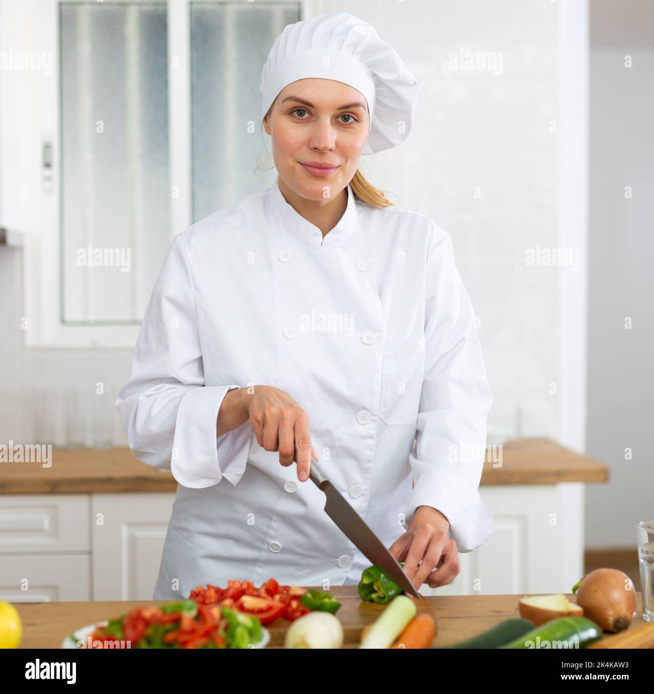 Proffesional woman cook in white uniform chopping vegetables Stock ...