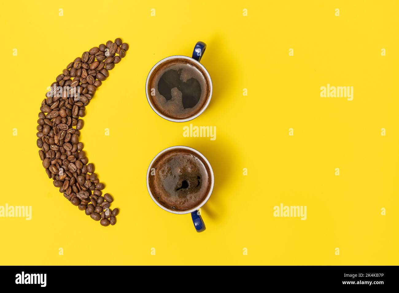 two cups of coffee and an emoticon made of coffee beans on a yellow ...