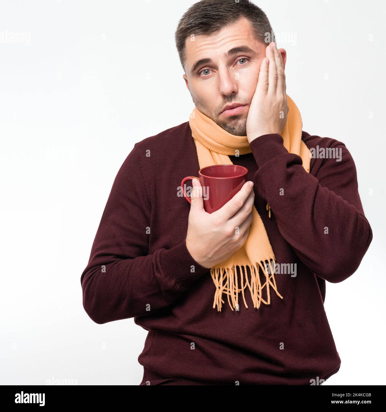 A handsome man touches his mouth with his hand with a pained expression ...