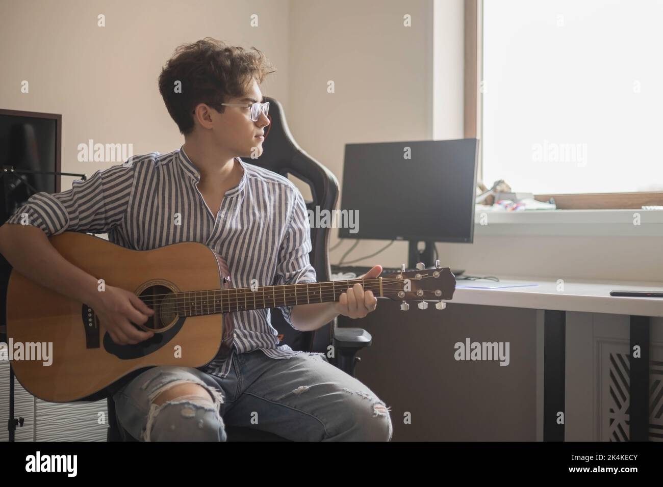 Male teenager singing song playing acoustic guitar reading text on ...