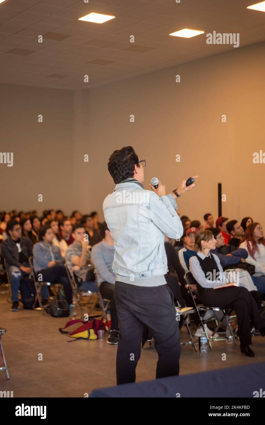 students paying attention to a lecture given by a woman, projecting ...