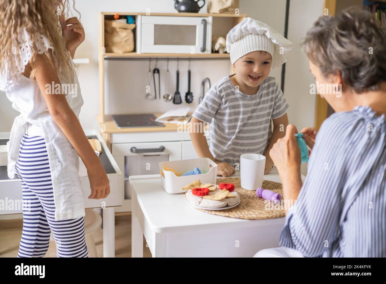 Mother and cute baby boy and girl cooking food at childish kitchen ...