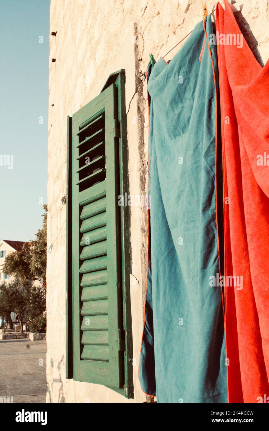 The vertical view of laundry hanging by the green vintage window of a ...