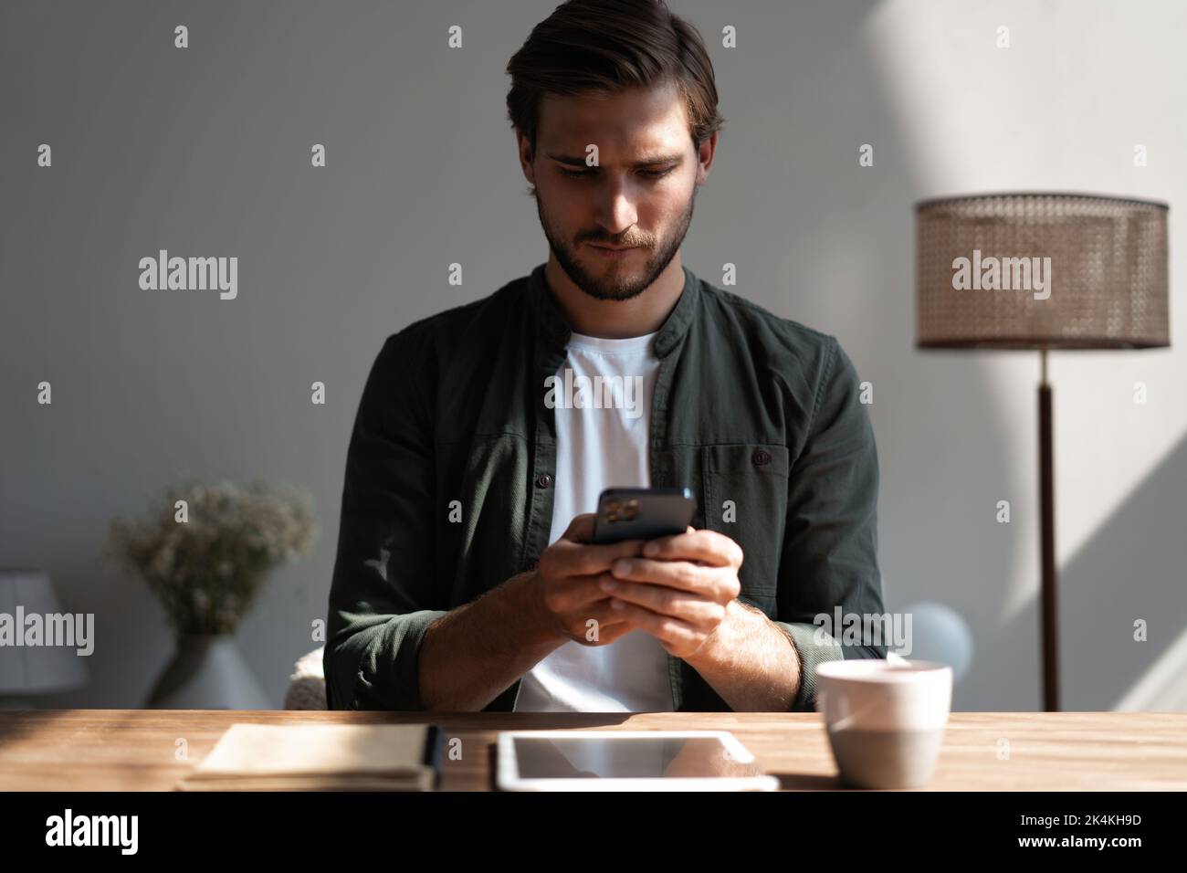 Young employee at workplace using mobile phone, checking social media ...