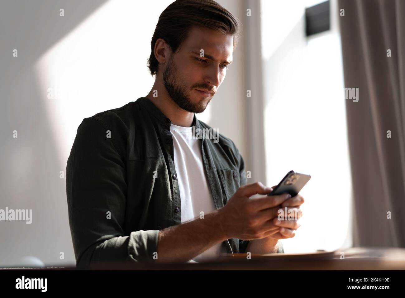 Young employee at workplace using mobile phone, checking social media ...
