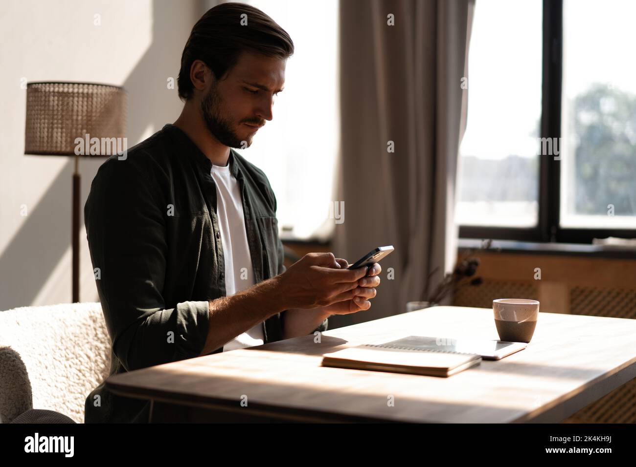 Young employee at workplace using mobile phone, checking social media ...