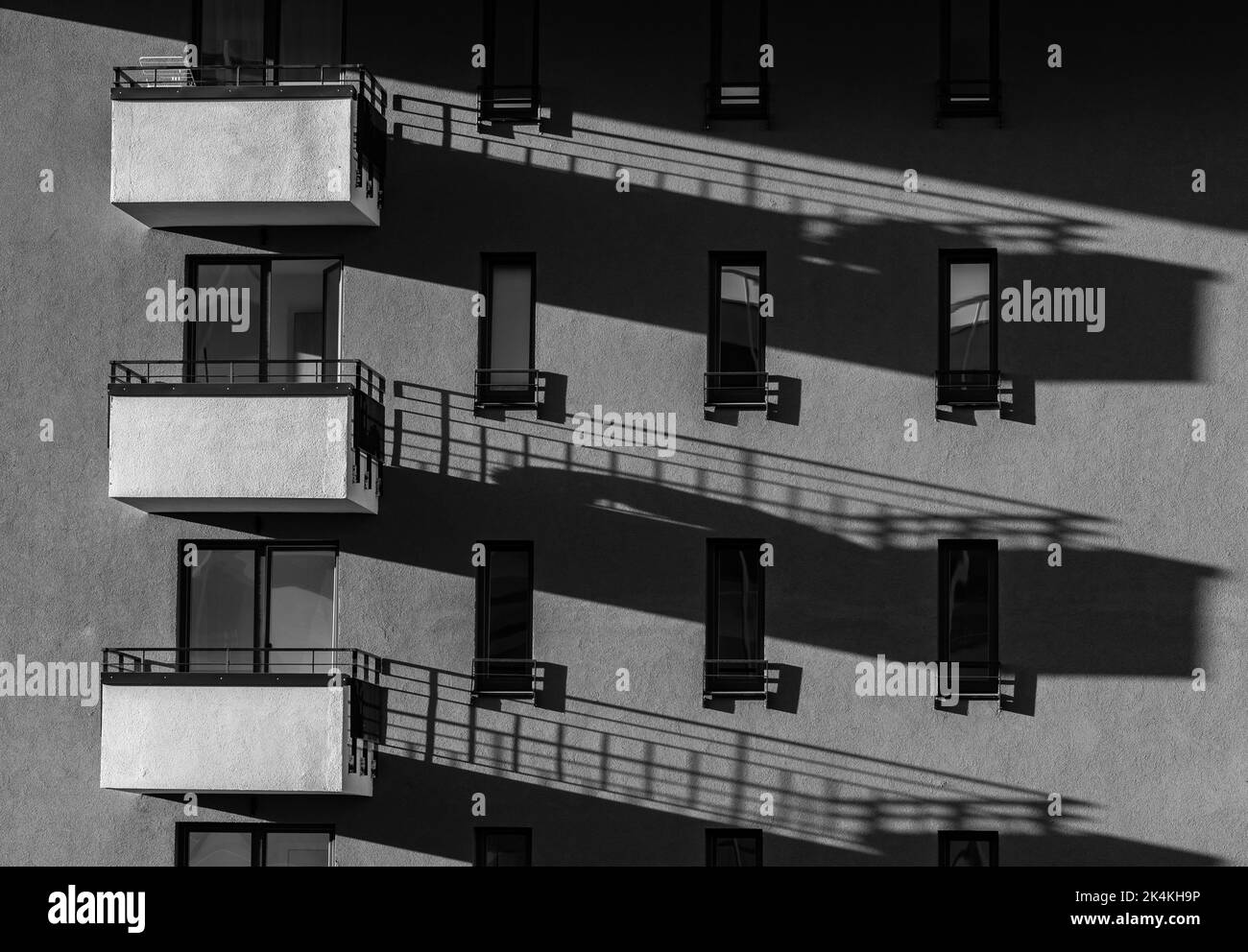 A grayscale of a building's balconies and windows with their shadow on ...