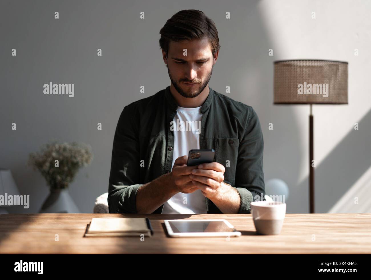 Young employee at workplace using mobile phone, checking social media ...