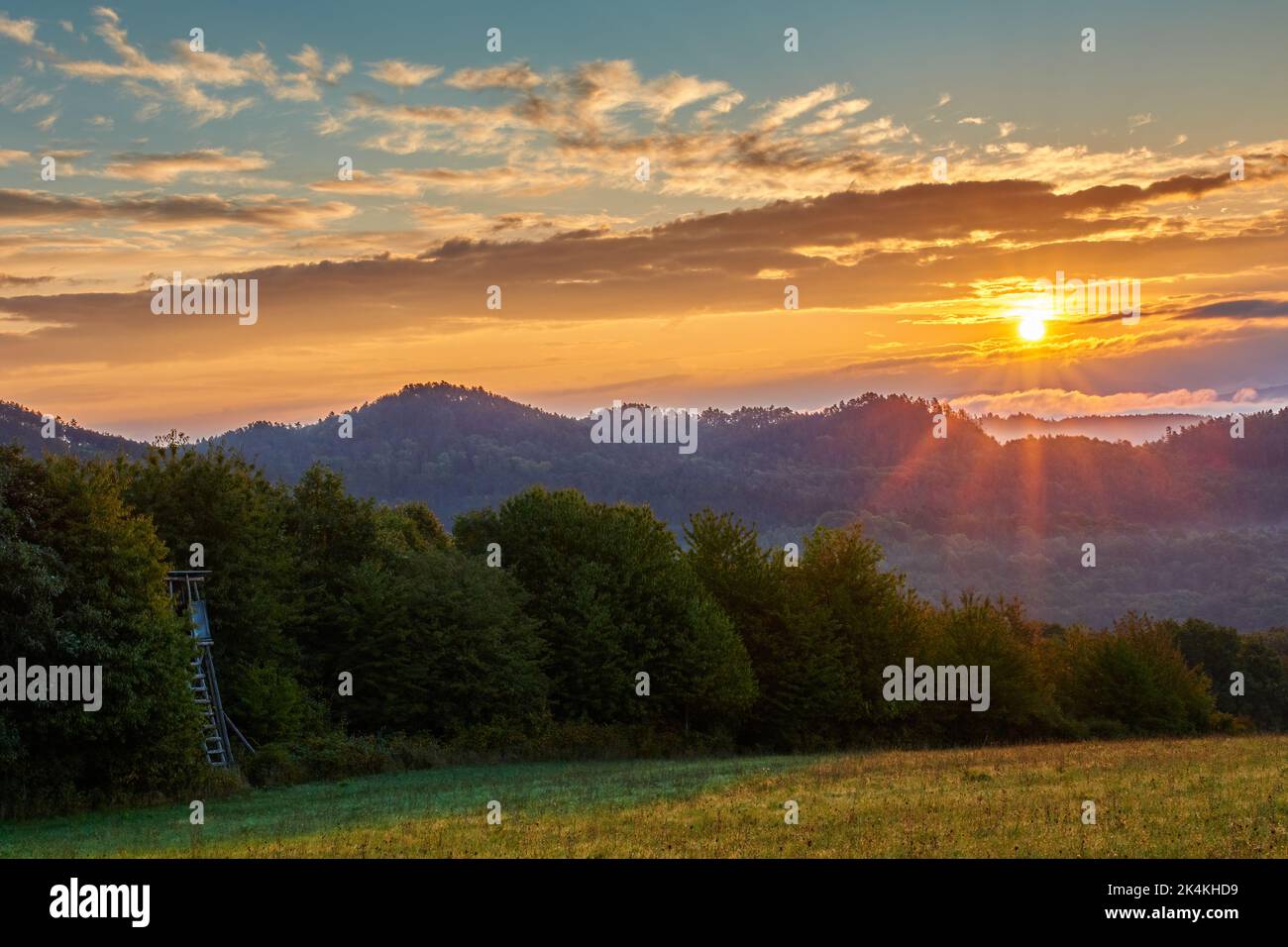 Sunrise in mountain landscape with sunstar. With trees and hills in the ...