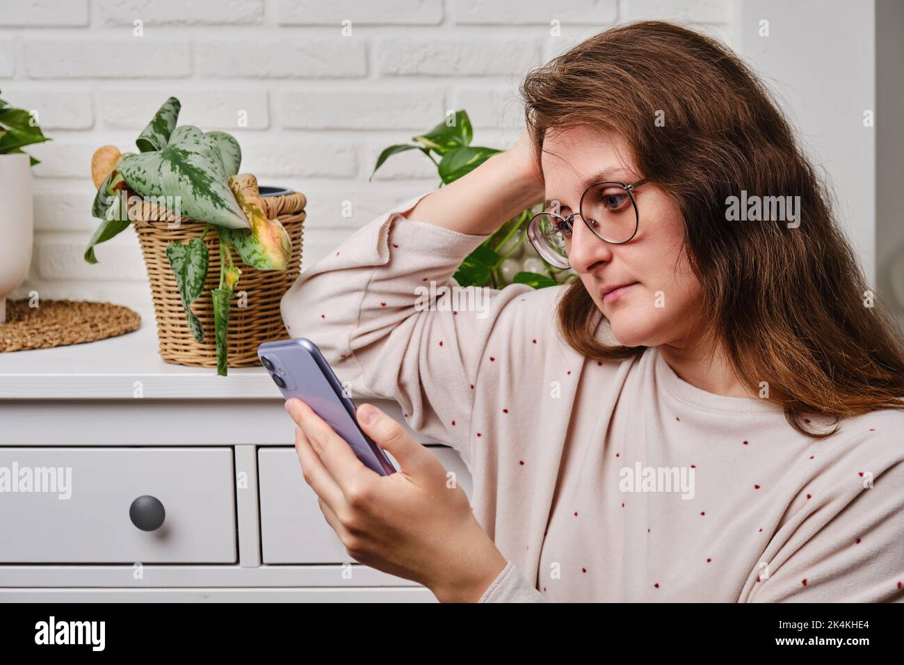 A sad woman gardener looks into the phone how to care for a withered ...