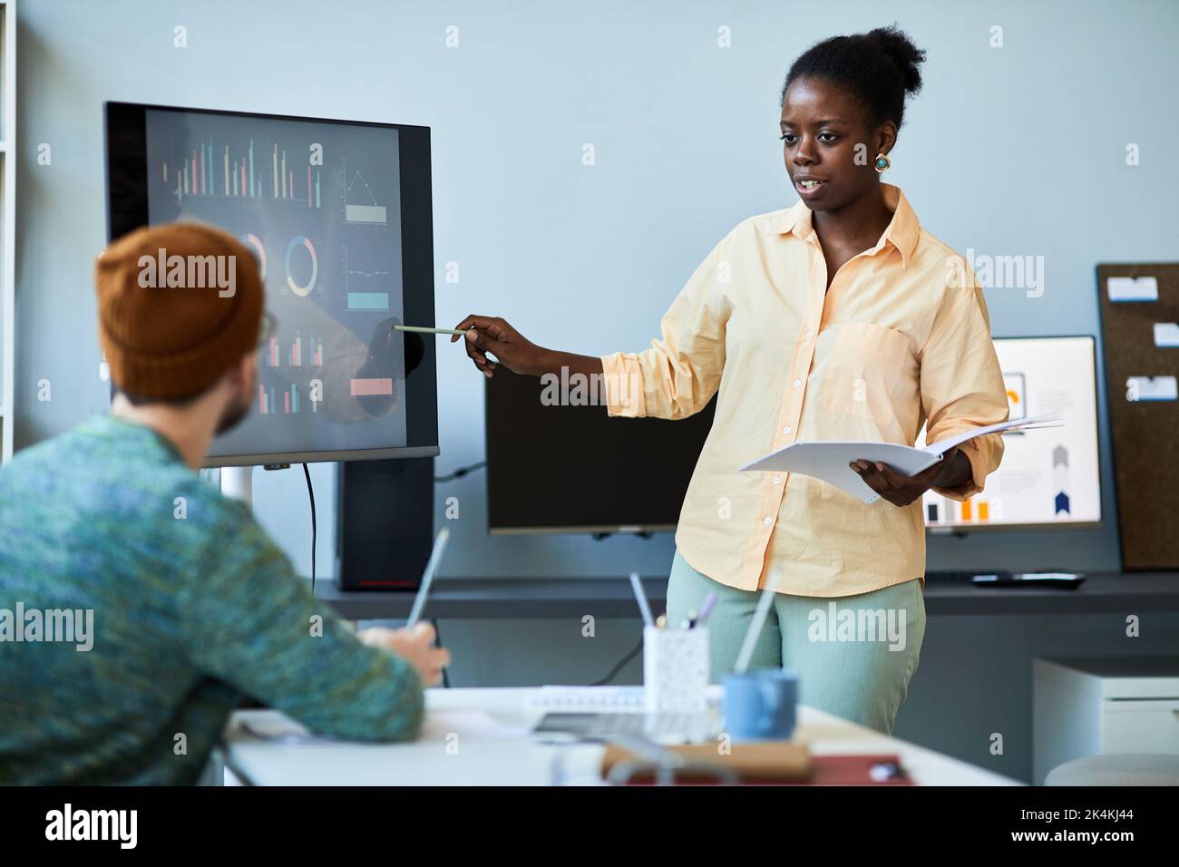 Confident coach pointing at interactive screen with graphic data at ...