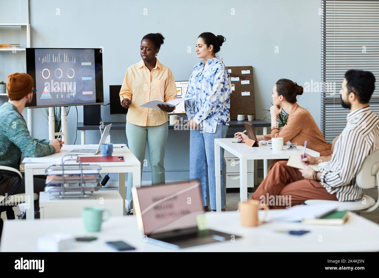 Young confident teacher or coach standing in front of audience at ...