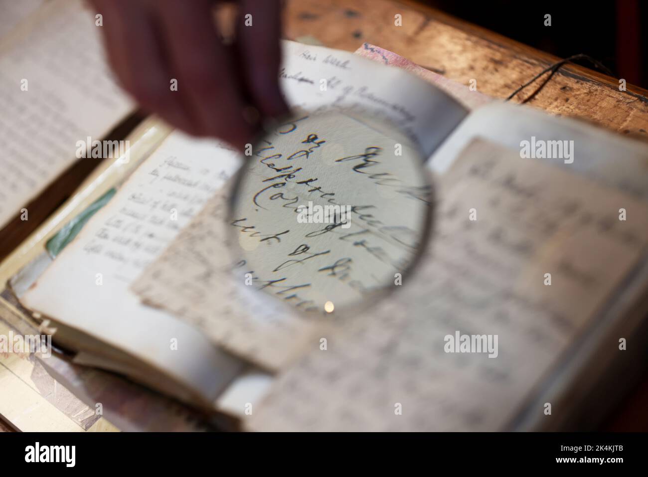 Old fashioned books and a magnifying glass showing hand writing from ...
