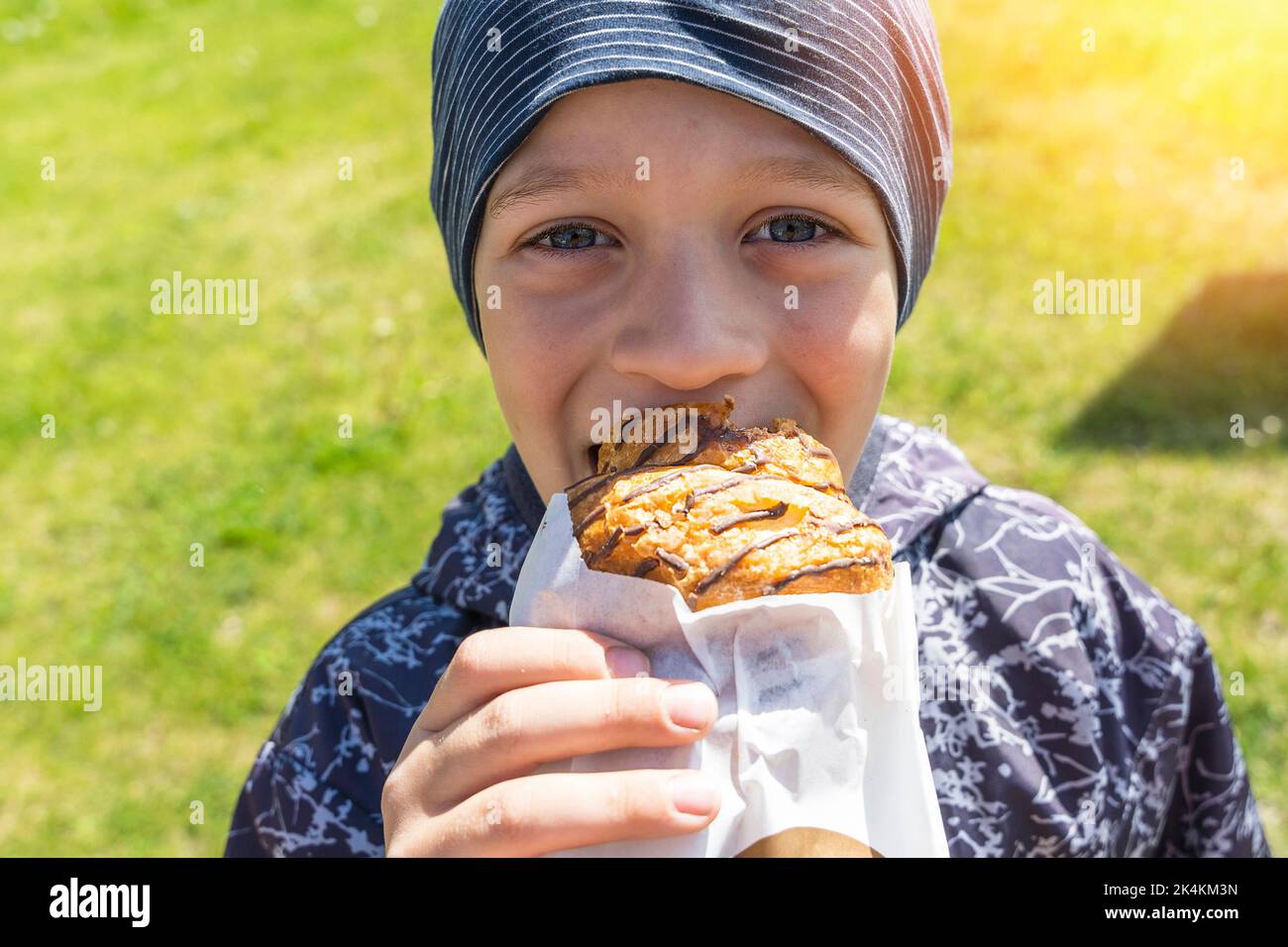 a cheerful cheerful boy is eating a bun on the street Stock Photo - Alamy